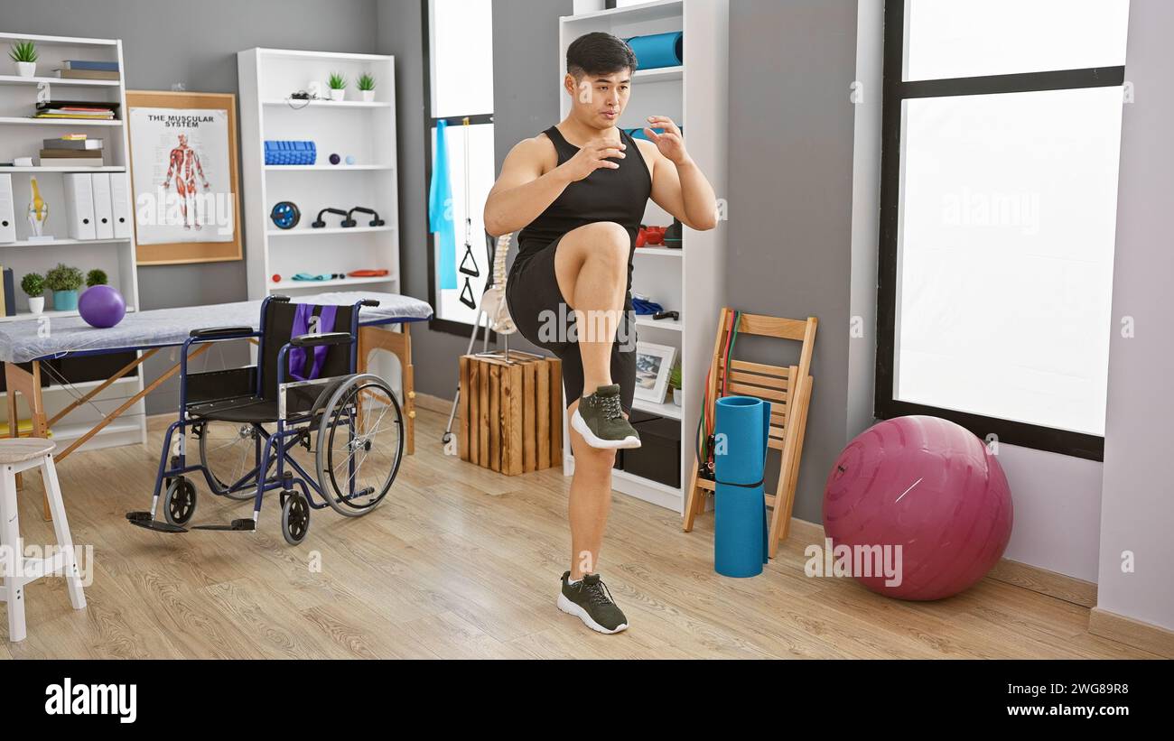 A young asian man exercises in a rehab clinic, balancing on one foot ...