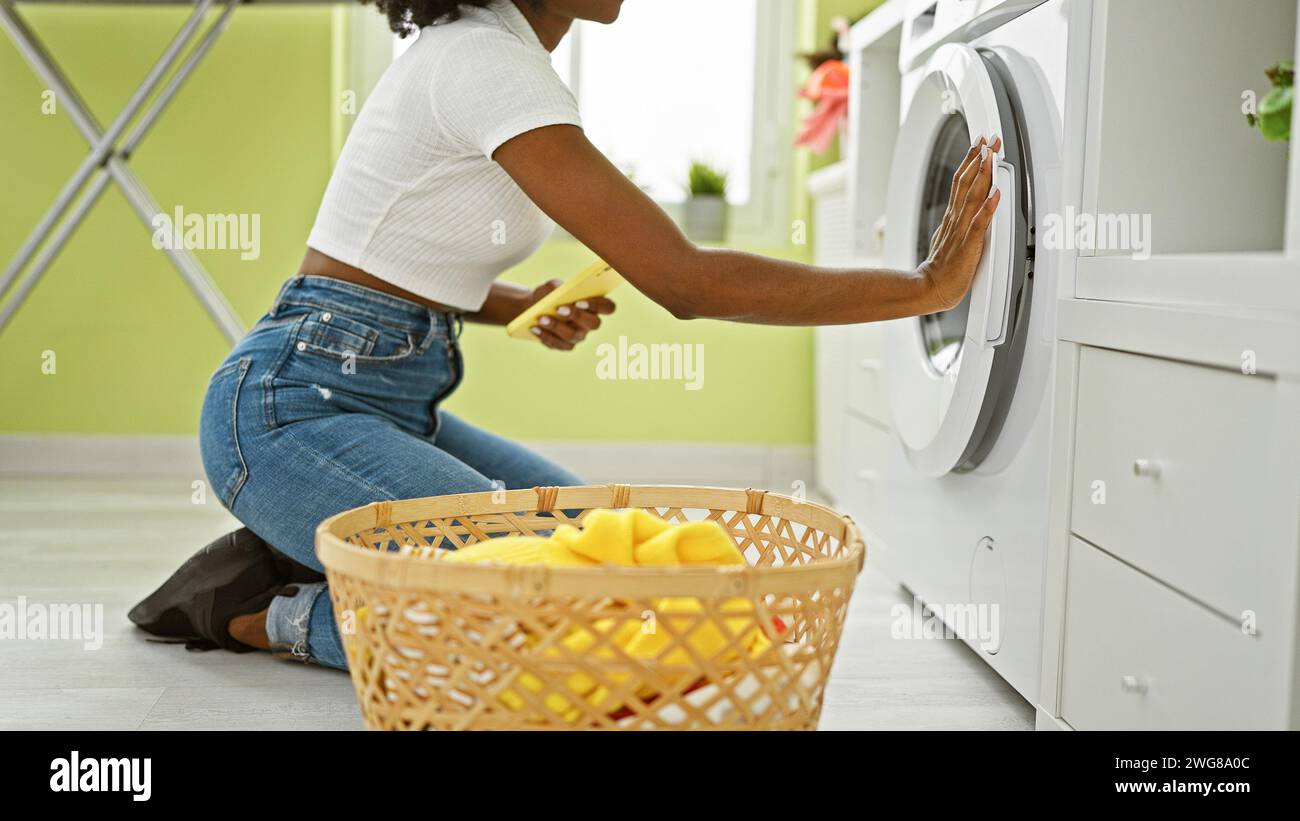 African american woman washing clothes starting washing machine by ...