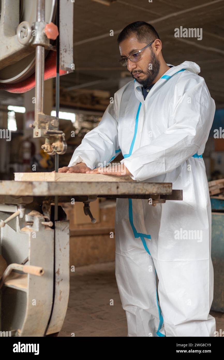 attractive young man wearing overalls and working with cutting machine ...