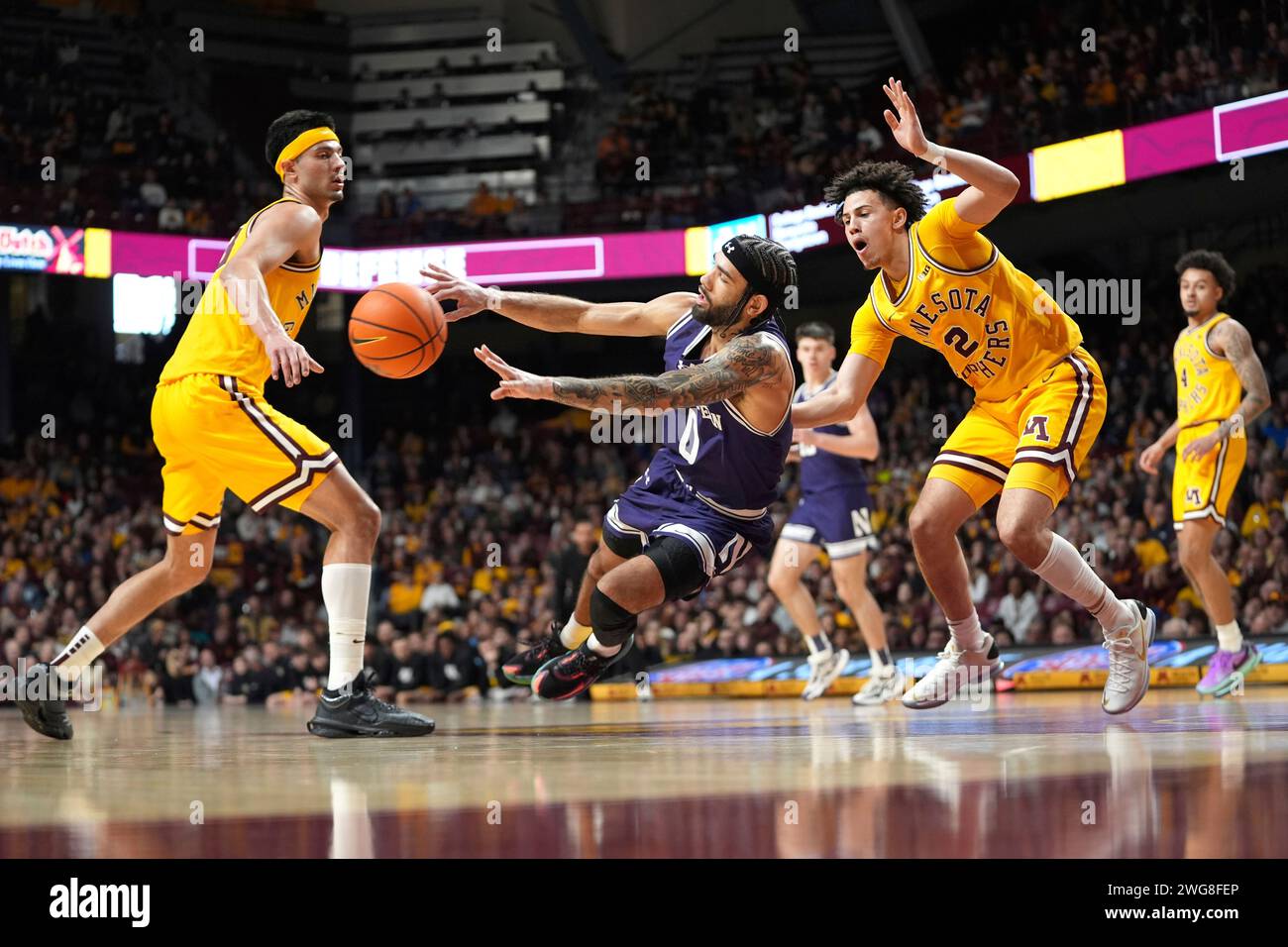 Northwestern guard Boo Buie, center, passes as Minnesota forwards ...