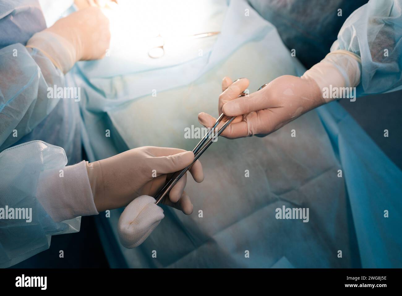 Top view of unrecognizable female nurse assists male surgeons, giving ...