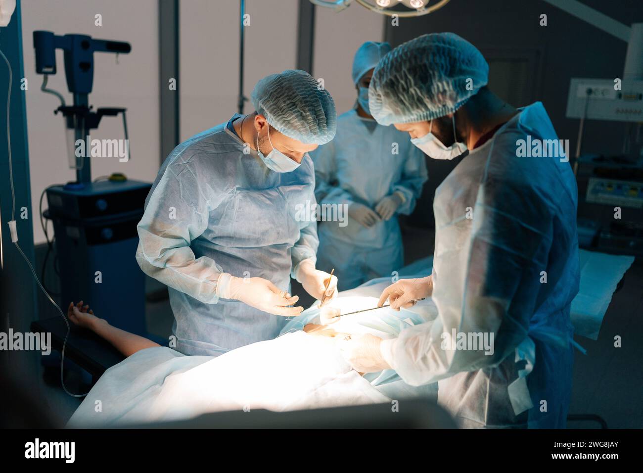 Remote view diverse team of professional surgeons performing invasive ...