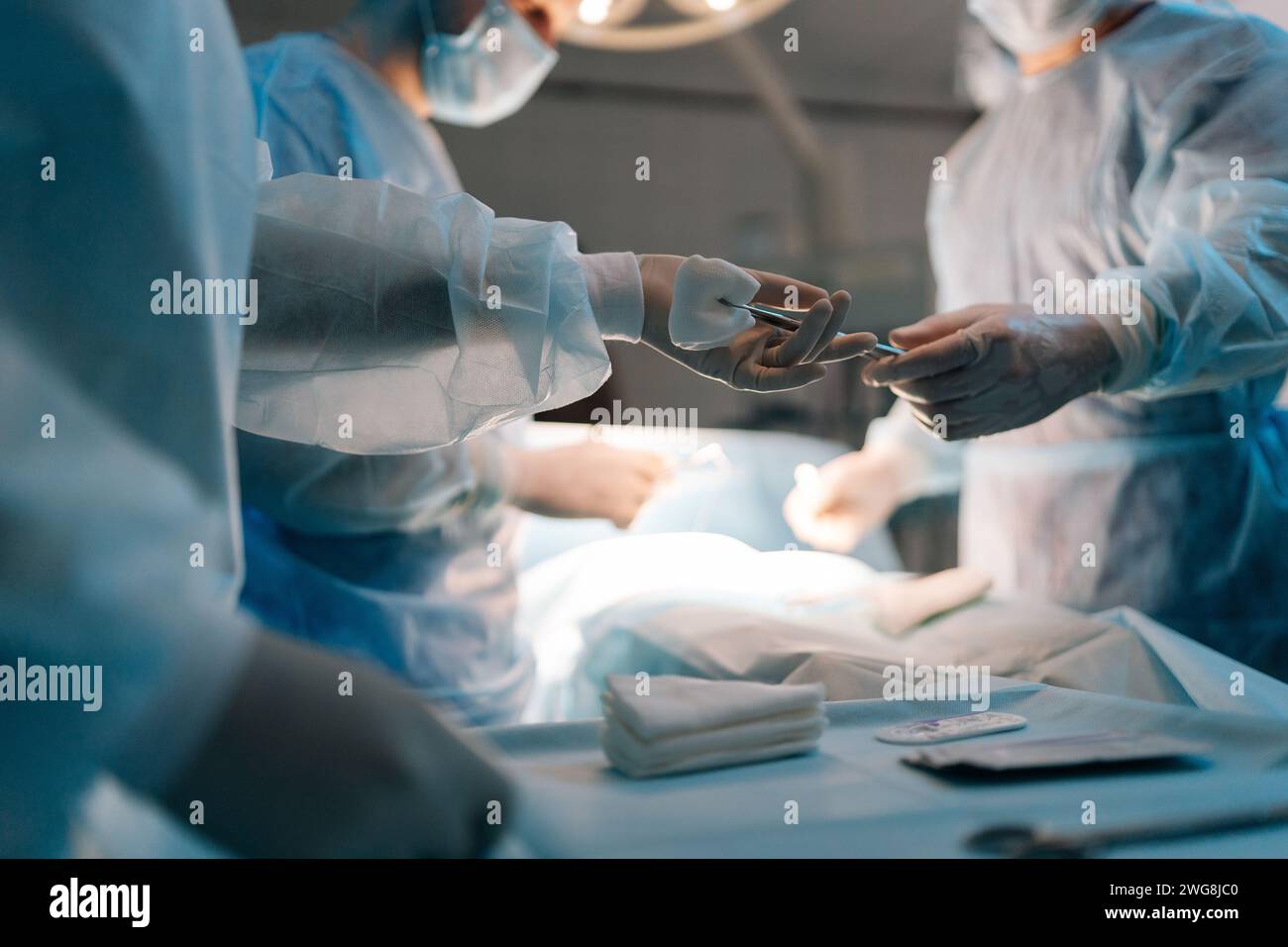 Closeup hands of unrecognizable nurse assists surgeons, giving surgical ...