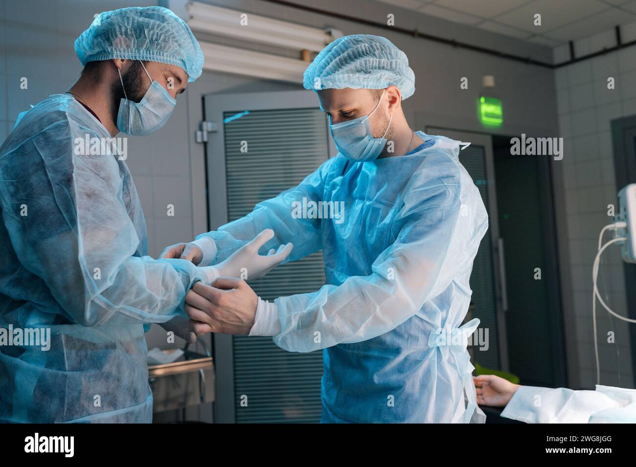 Portrait of practitioner helping surgeon putting on sterile medical ...