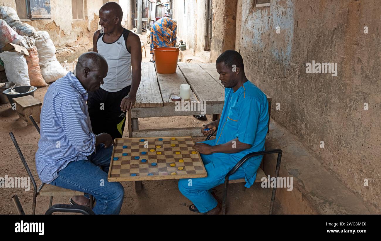 Two men play checkers game narrow alley neighborhood Nima Accra Ghana ...
