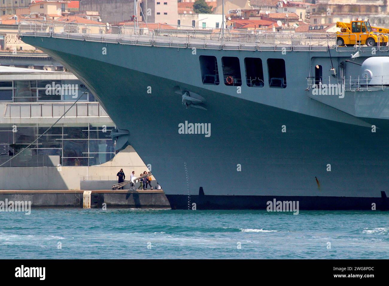 A group of people dwarfed by the imposing bow of the Italian aircraft carrier Giuseppe Garibaldi ...