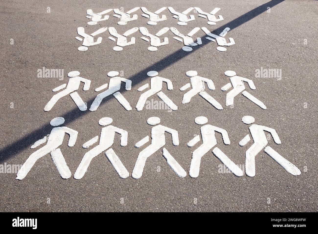 White painted symbols of people walking on a gray asphalt road ...