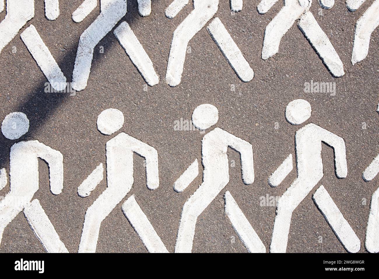 White painted symbols of people walking on a gray asphalt road ...