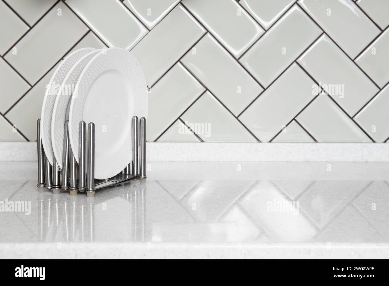 A stack of clean white plates in a plate rack on a reflective kitchen ...