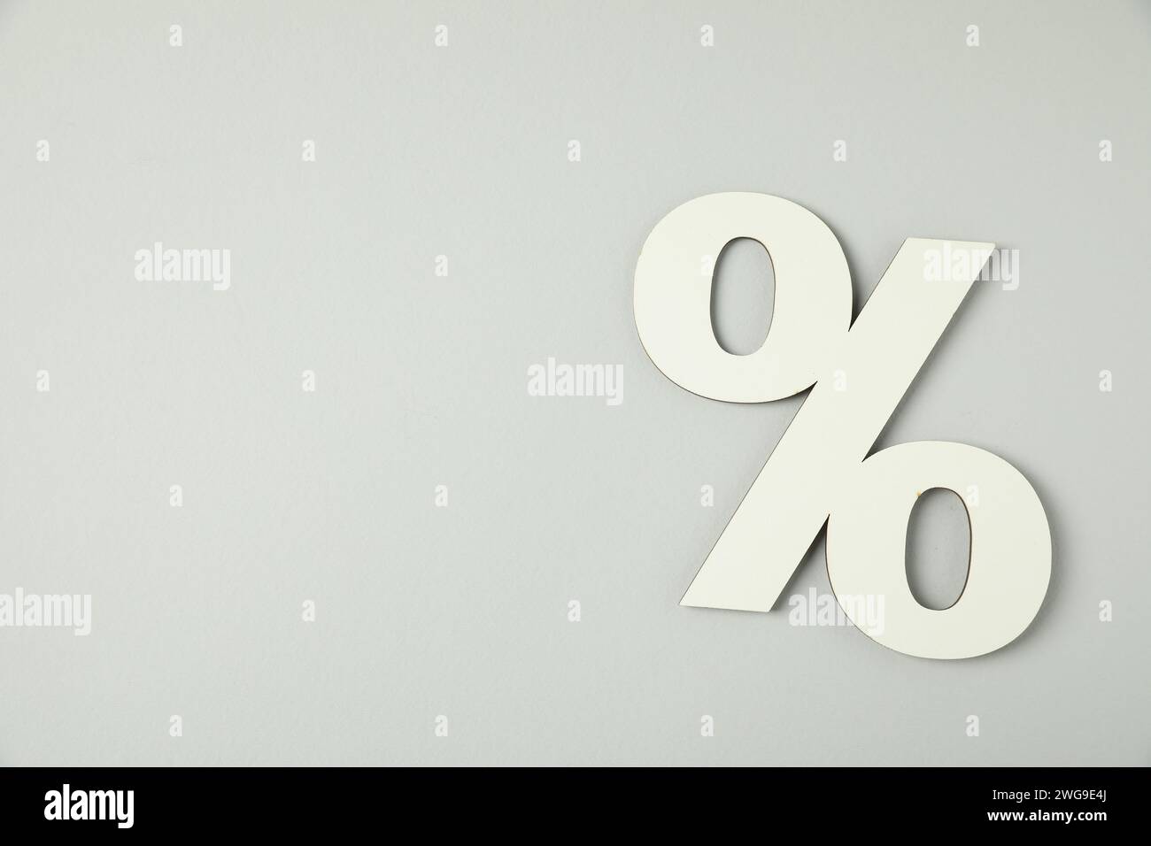 White percent sign on light grey background, top view. Space for text ...