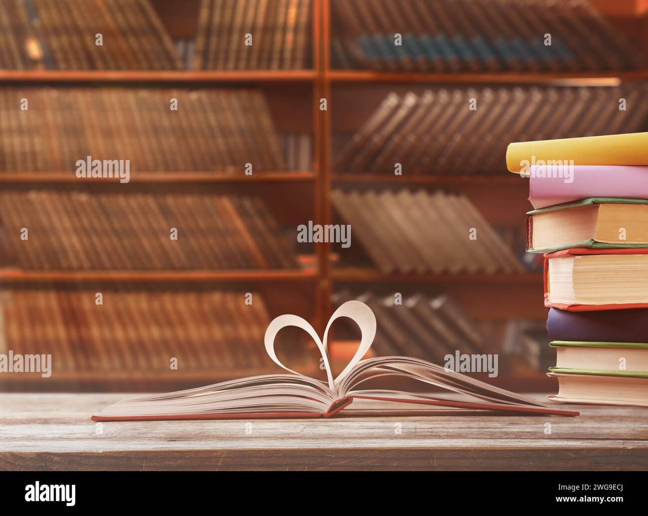 Open book with pages folded in heart in library Stock Photo - Alamy