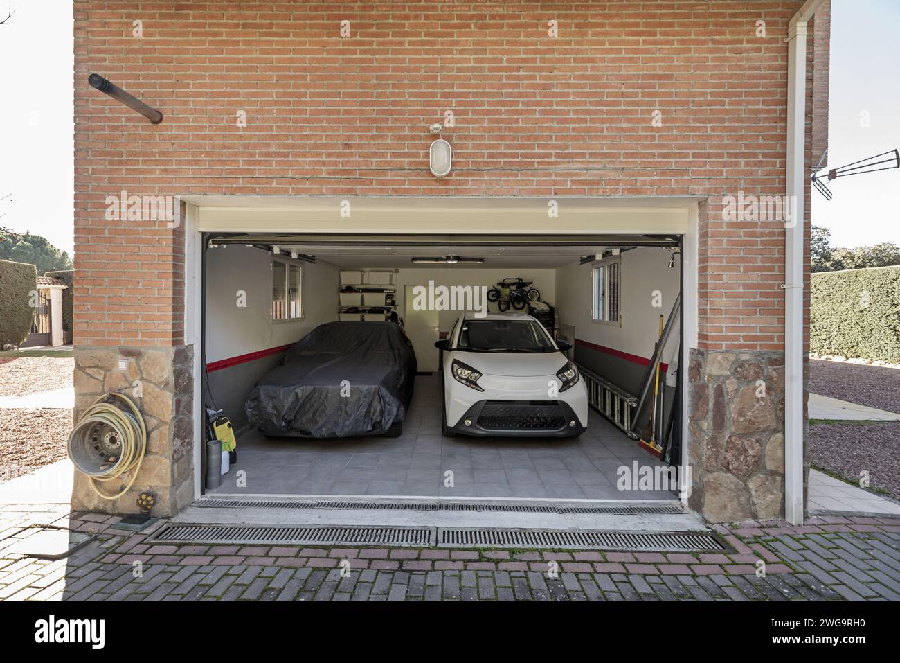 A garage of a single-family home with two cars parked, one of them ...