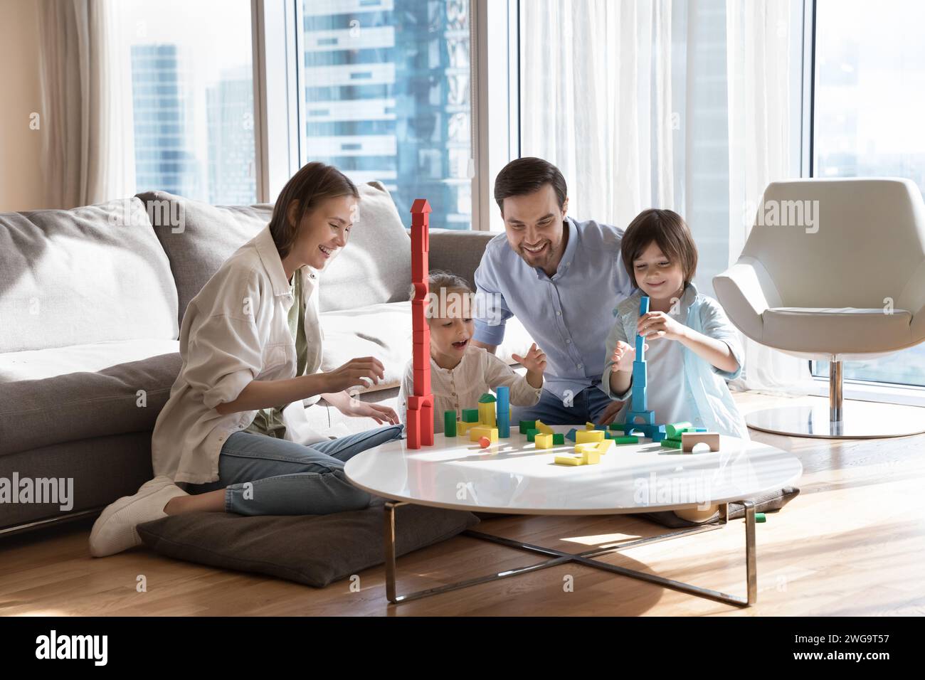 Parents and little children build towers from colored wooden cubes ...