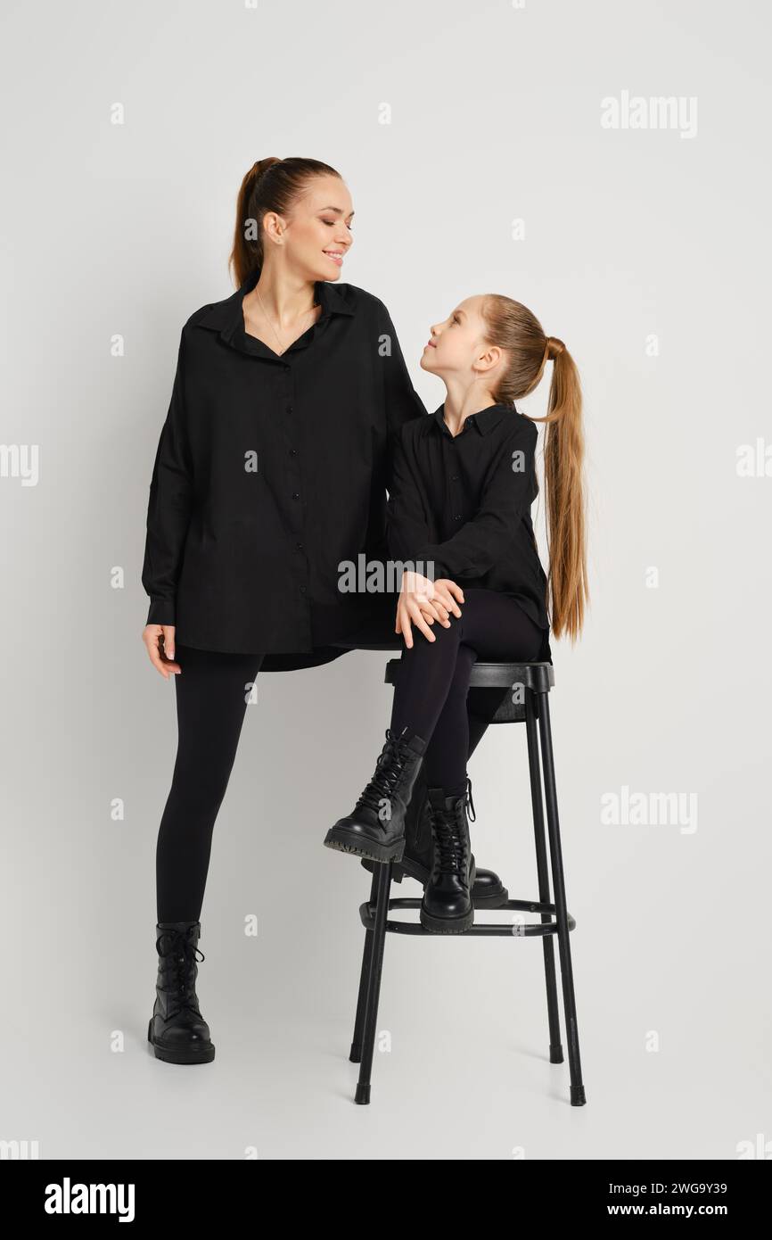 A modern family relations. Mother standing next to daughter sitting on ...