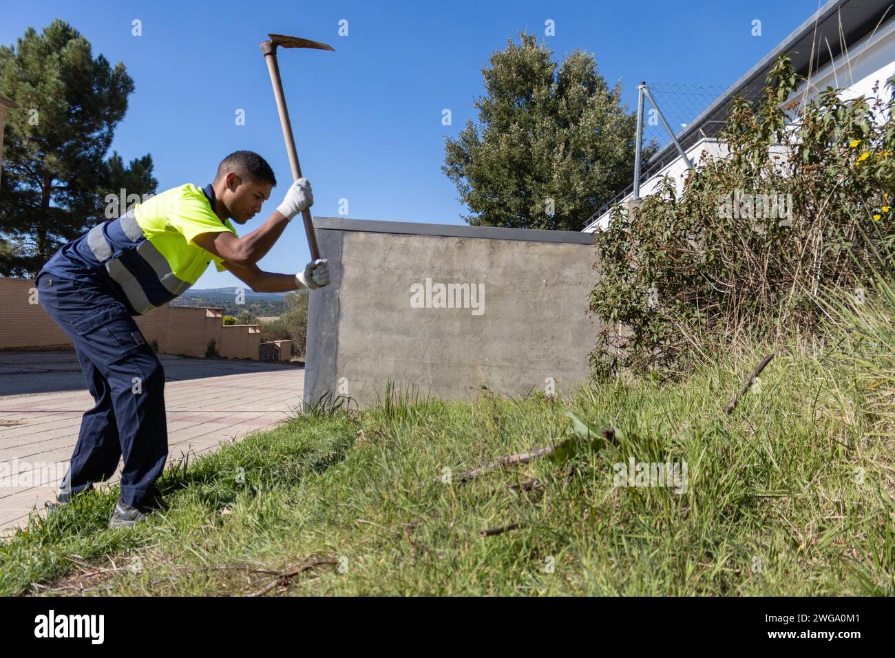 Black latino gardener working in work clothes in a city garden, digging ...