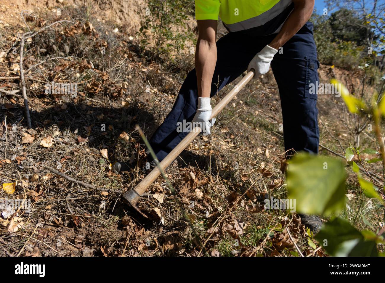 Unrecognizable person with gloves removing soil with a hoe, close up ...