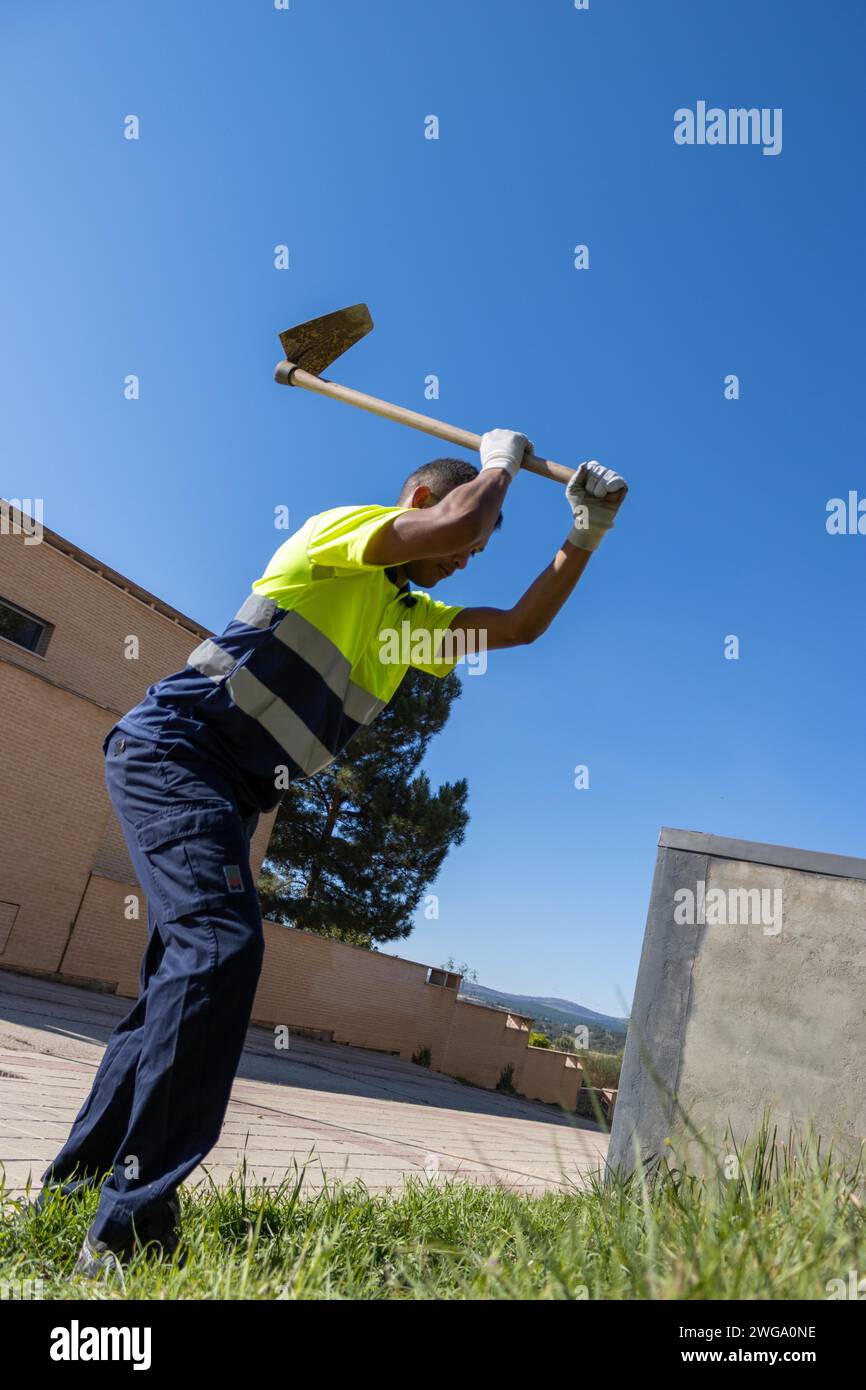 Vertical portrait of latin worker dressed in work clothes digging the ...