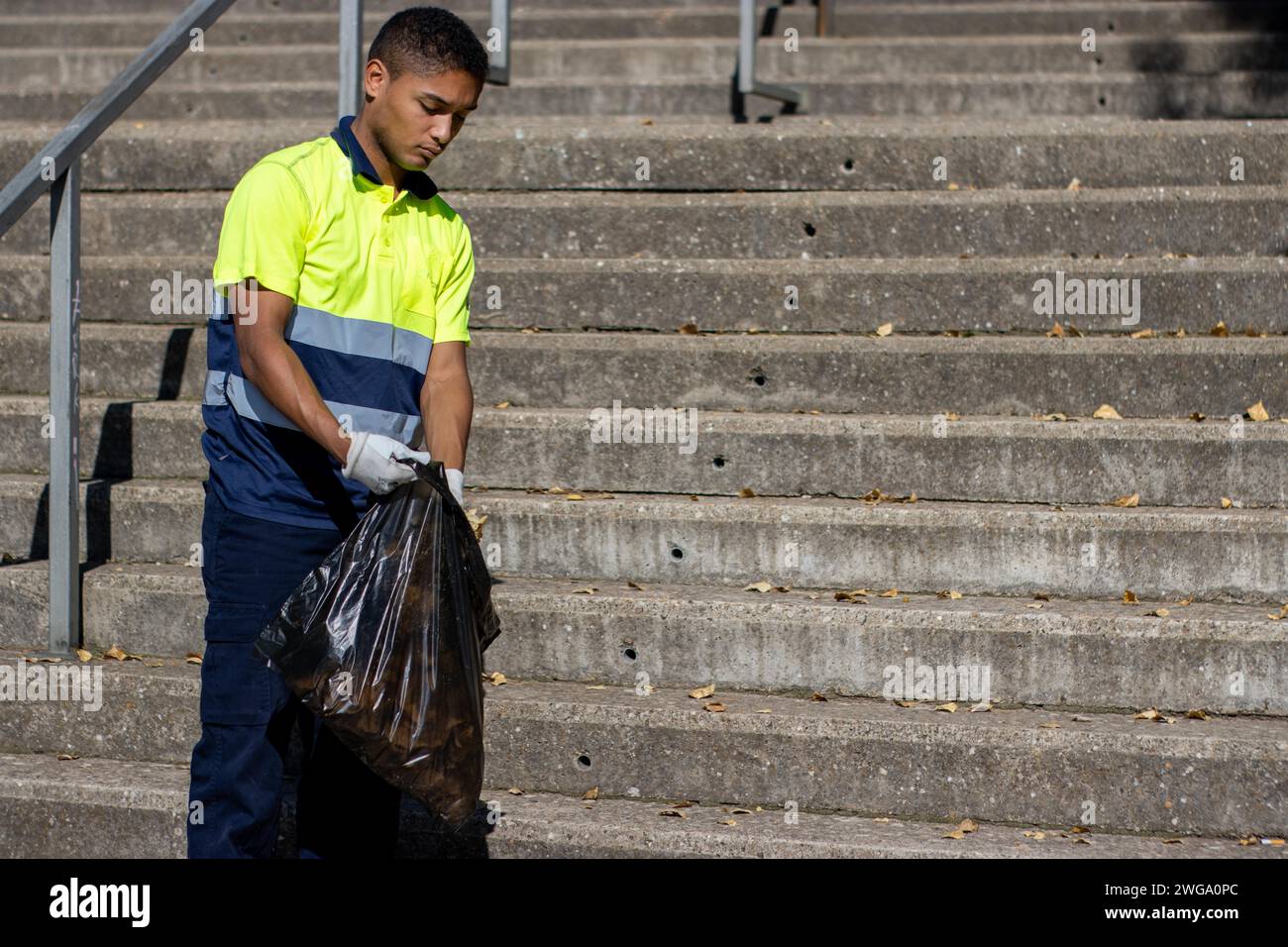 Portrait of a Latino male garbage collector in work uniform collecting ...