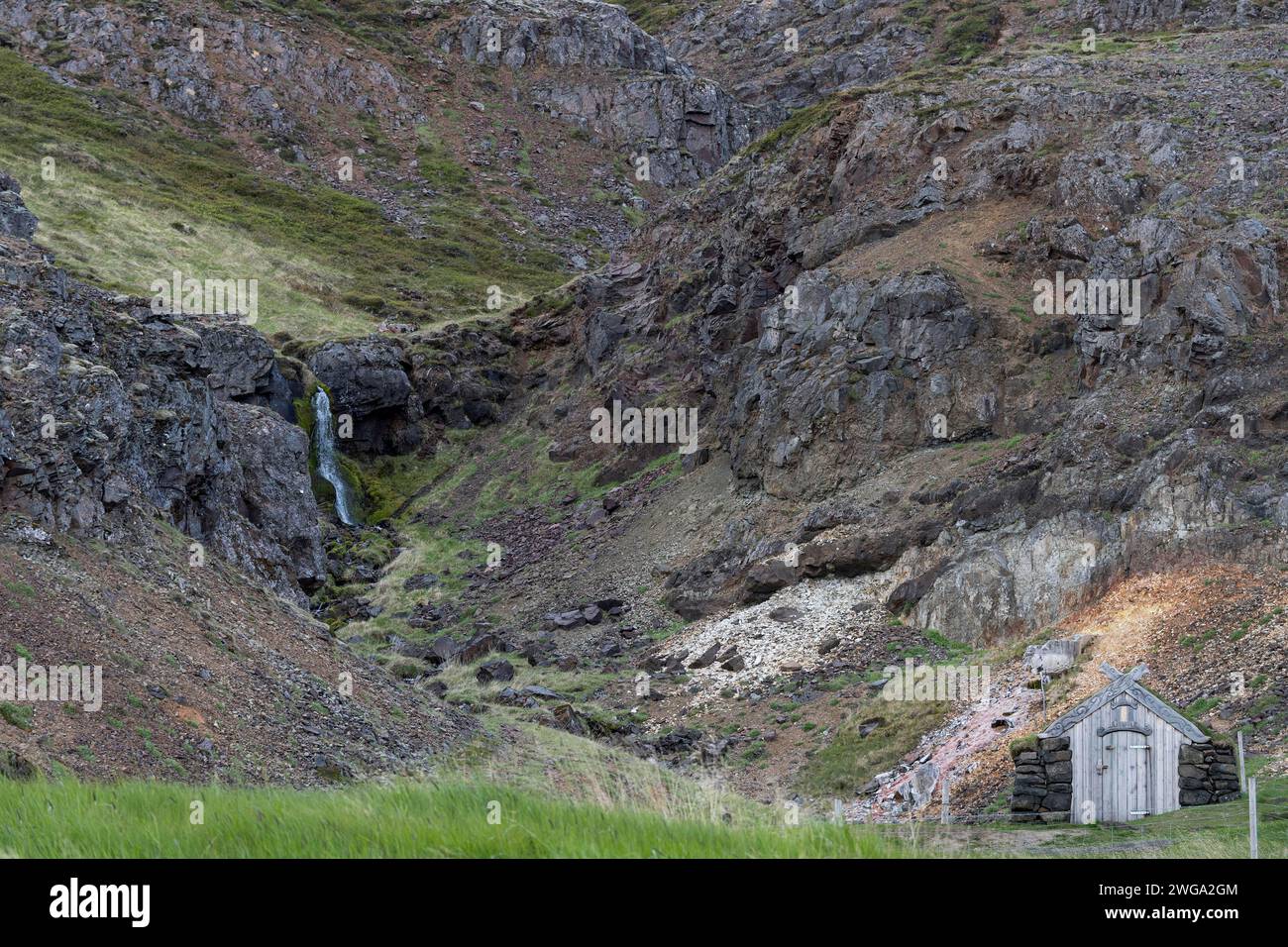 Old hut with stone walls and grass roof, waterfall, Laugar, Westfjords ...