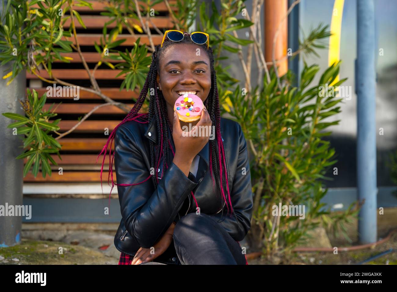 Cute and happy african girl with leather jacket and sunglasses eating a ...