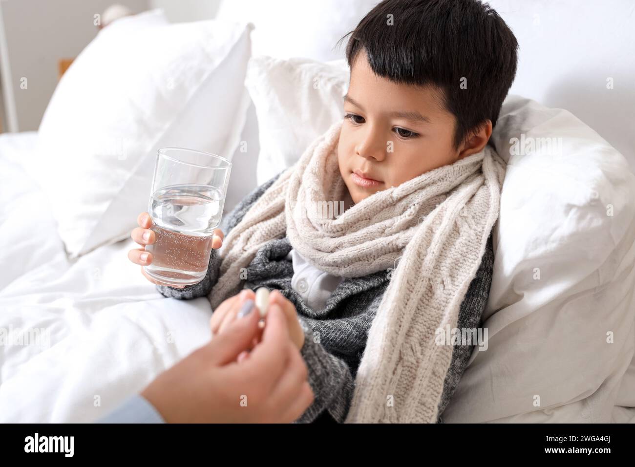Ill little Asian boy taking pill from his mother in bedroom Stock Photo ...