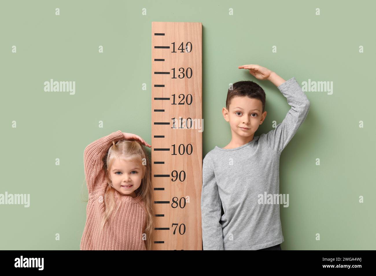Cute little children measuring height on green background Stock Photo ...