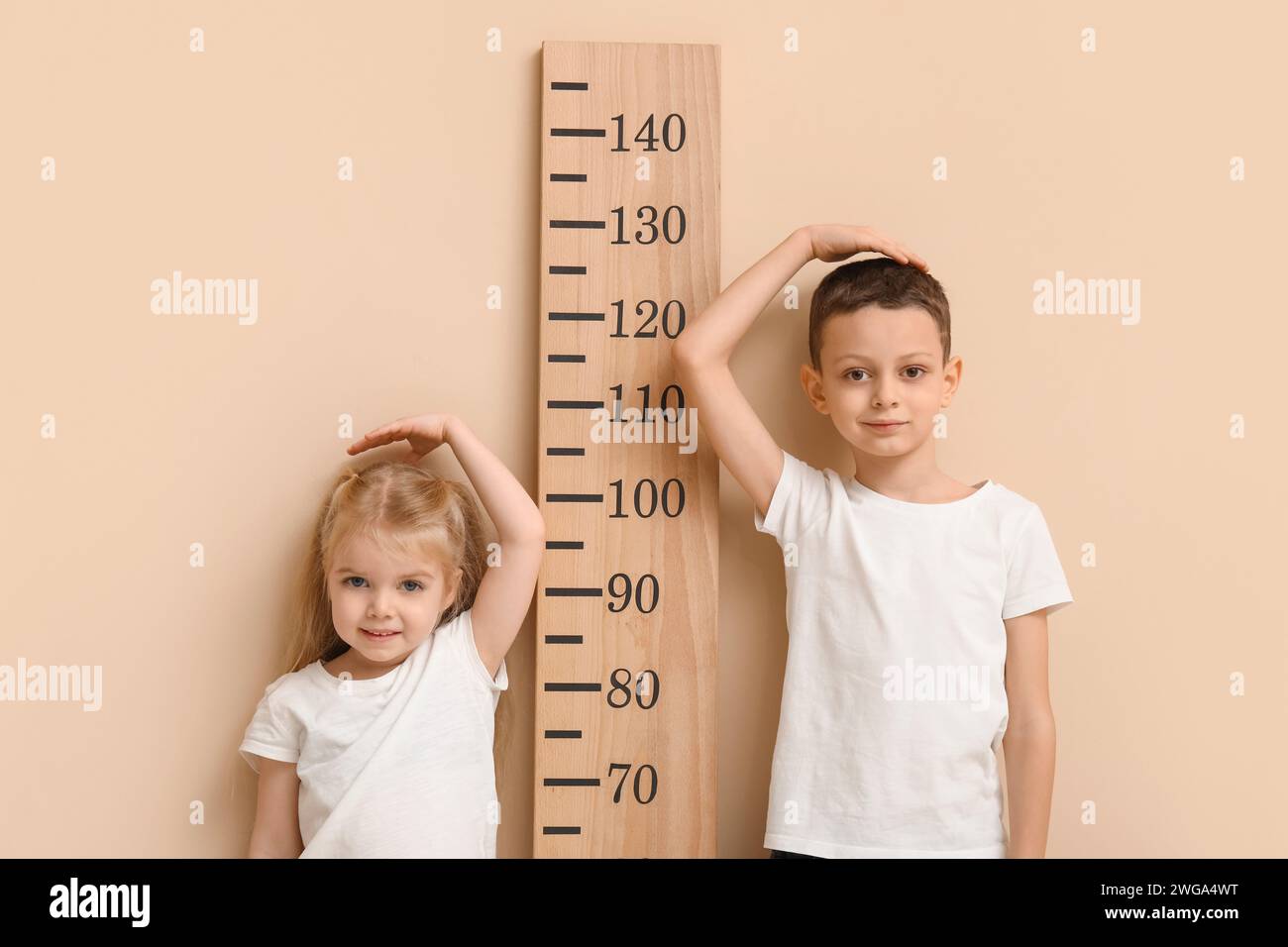 Cute little children measuring height on beige background Stock Photo ...