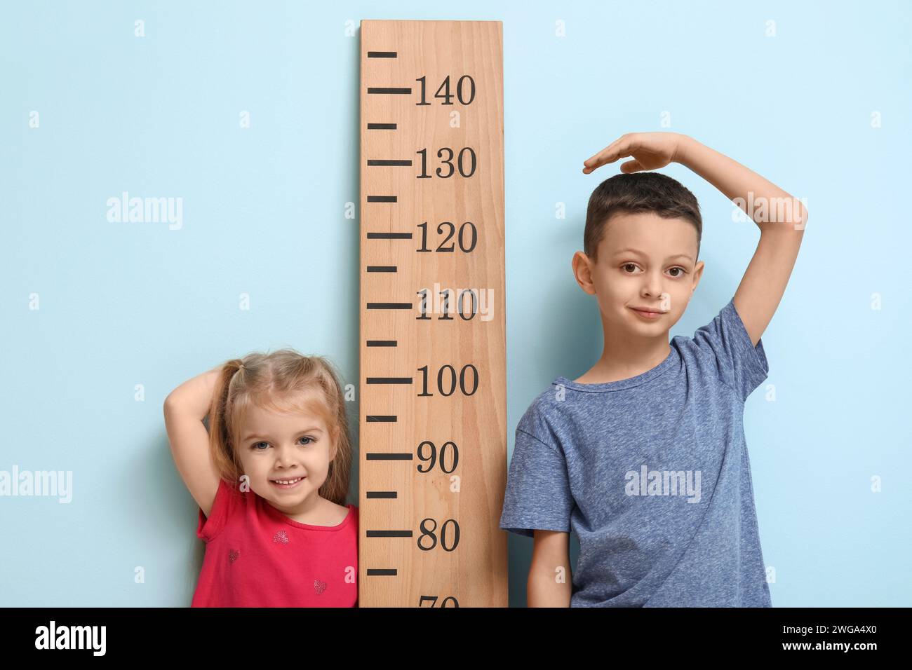 Cute little children measuring height on blue background Stock Photo ...