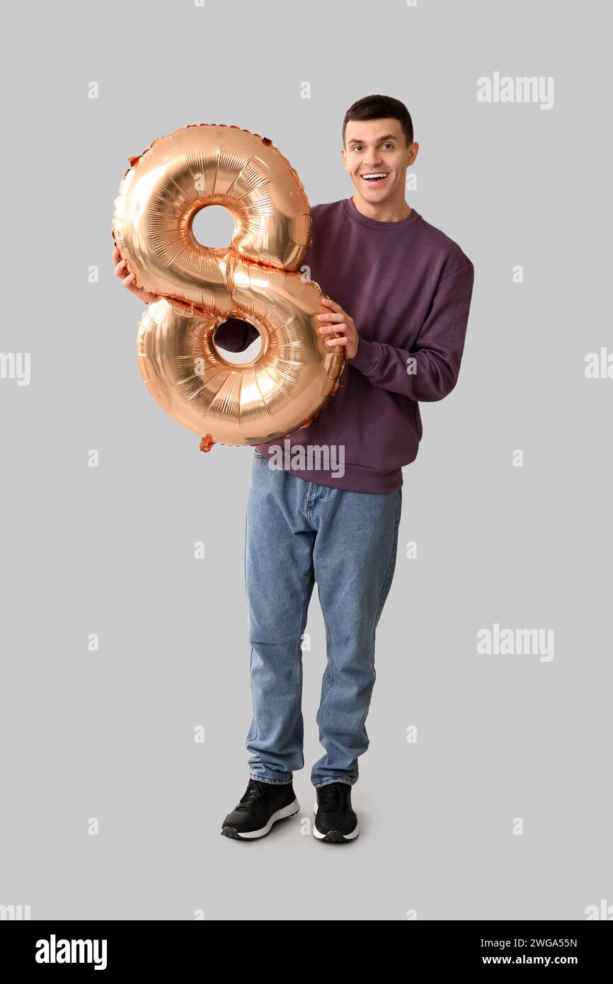 Handsome man holding balloon in shape of figure 8 on white background ...