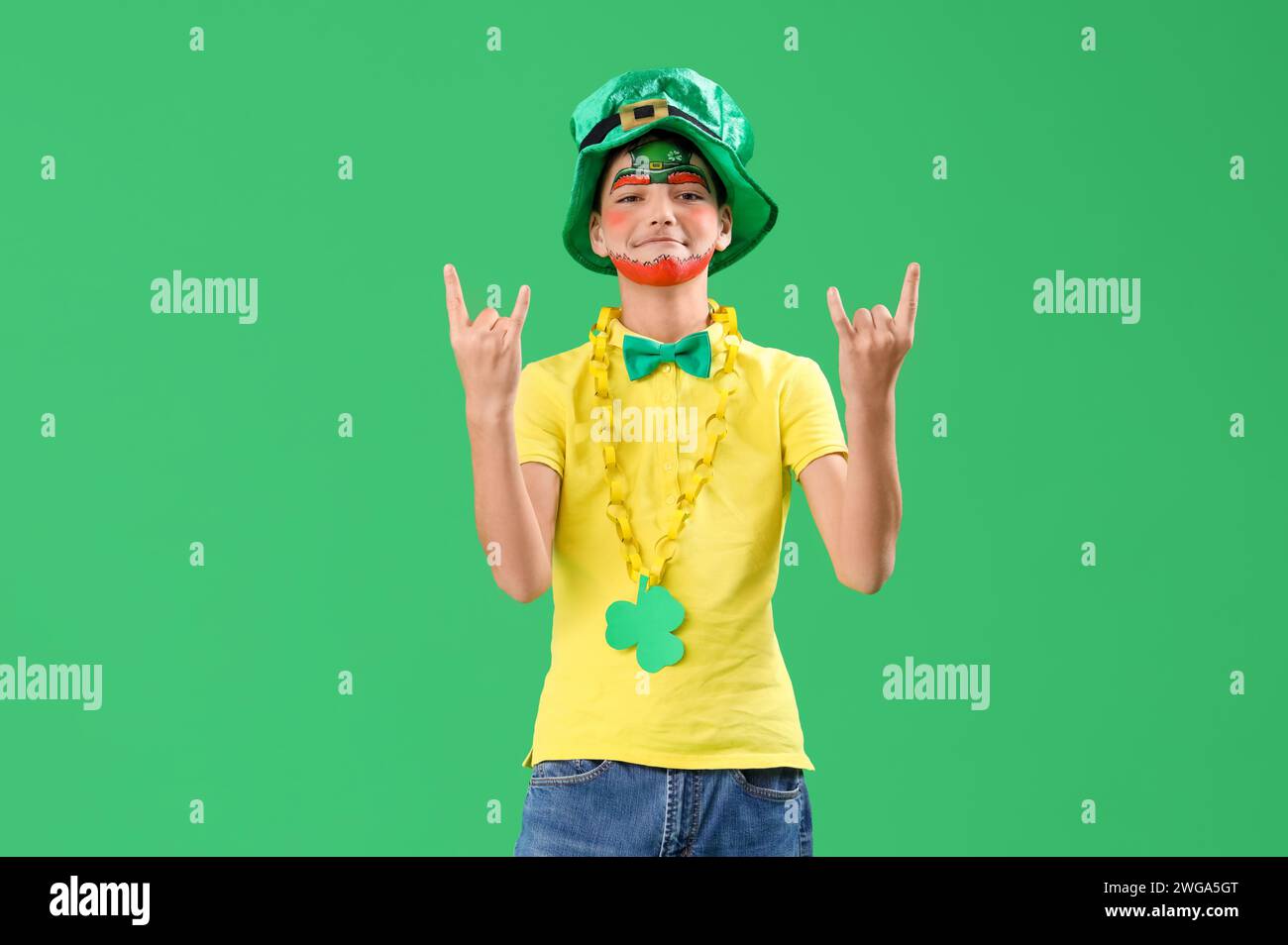 Funny boy with face painting and leprechaun's hat showing "devil horns ...