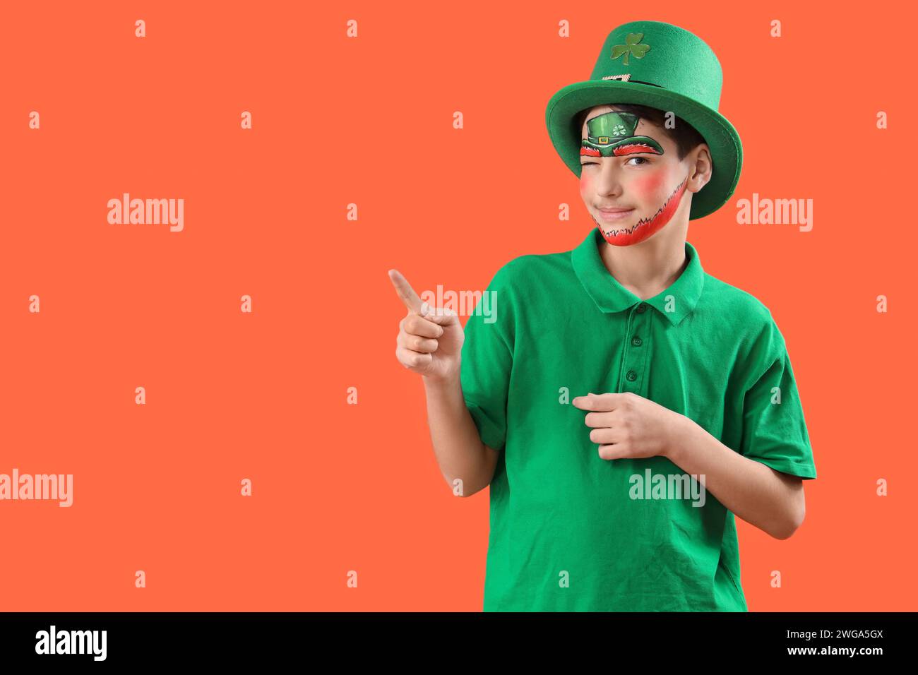 Funny boy with face painting and leprechaun's hat pointing at something ...