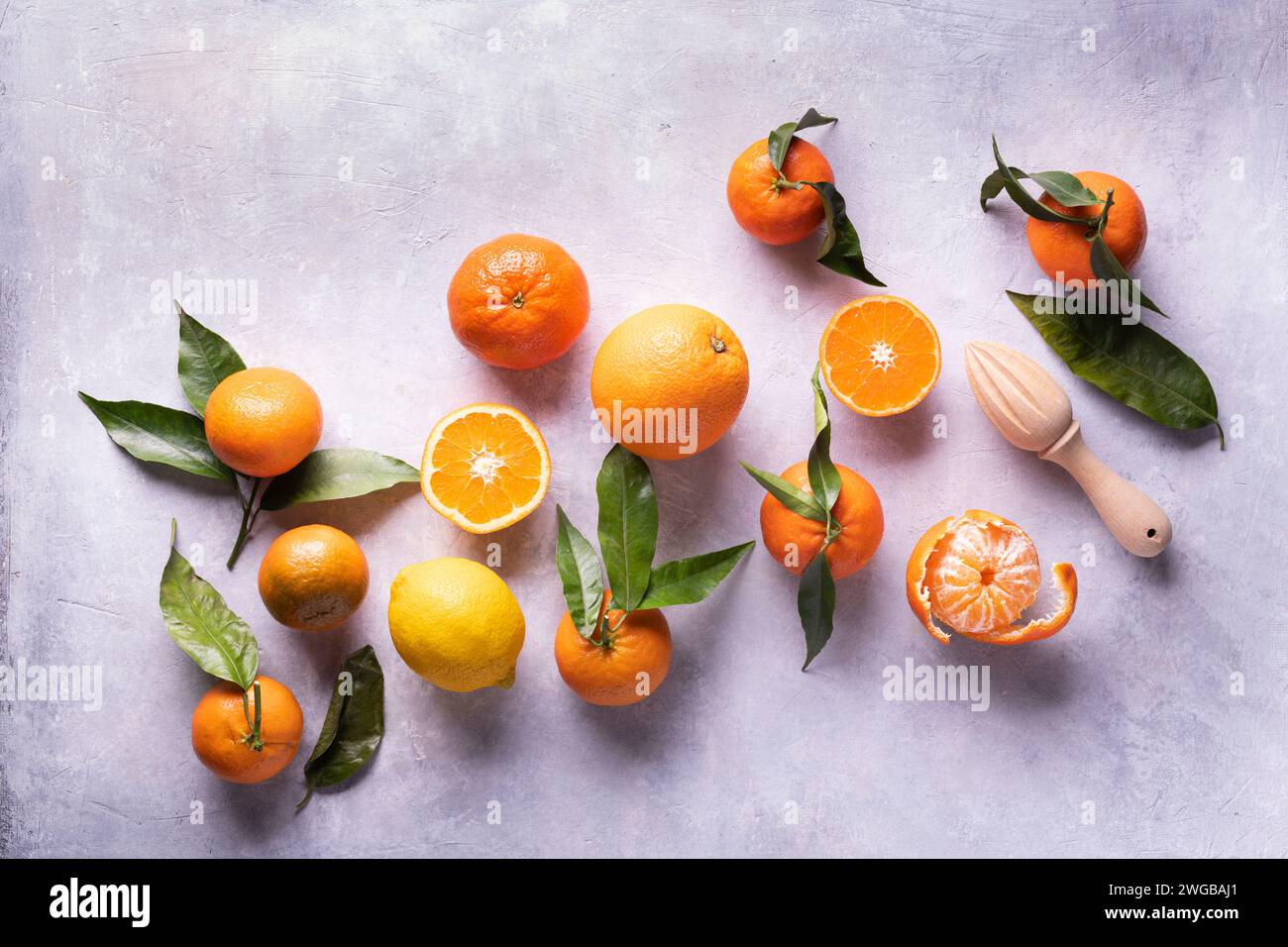 Types of green leafy, whole and sliced citrus fruits are arranged on a ...