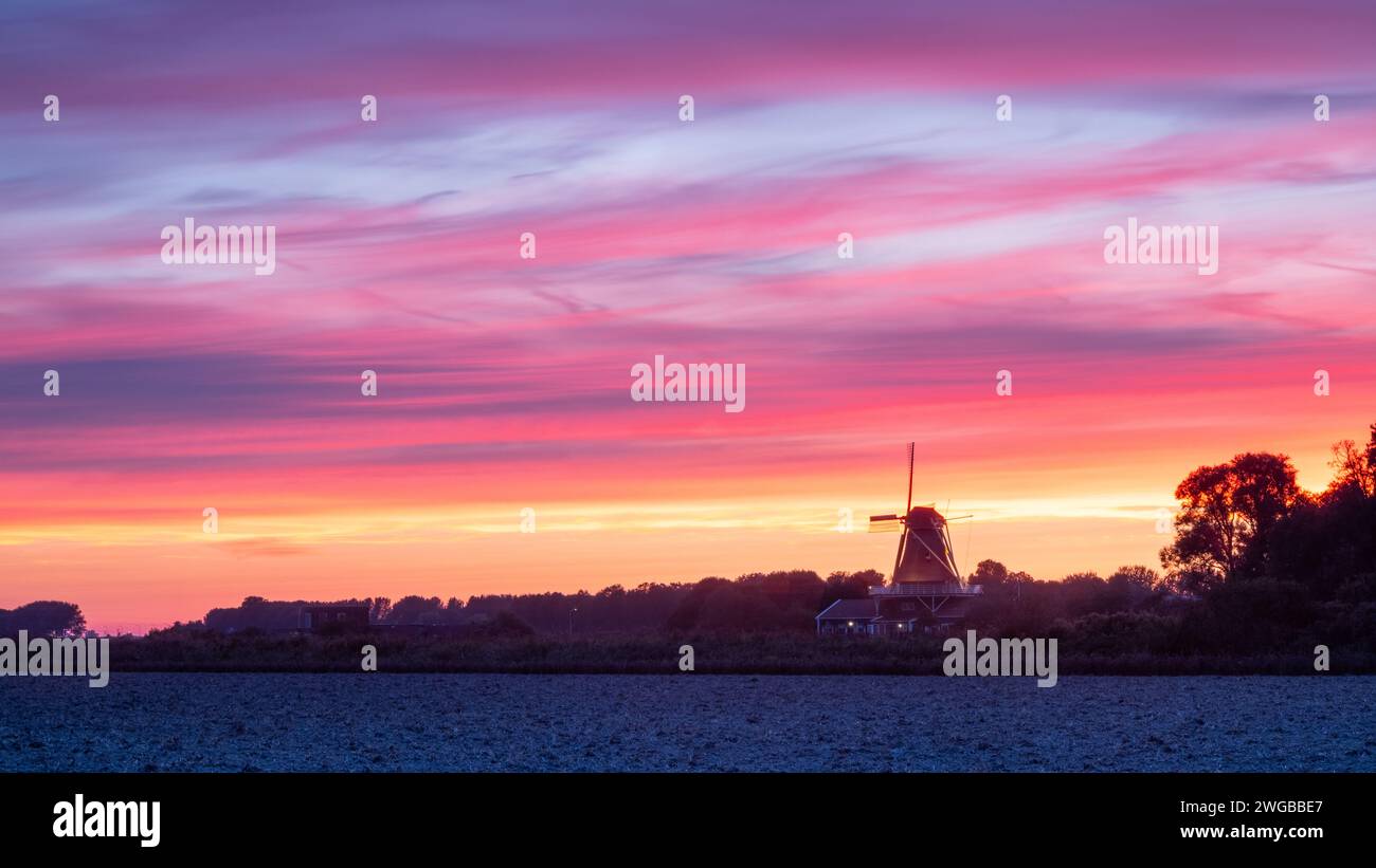 A typical Dutch windmill is illuminated by the breathtaking colors of ...