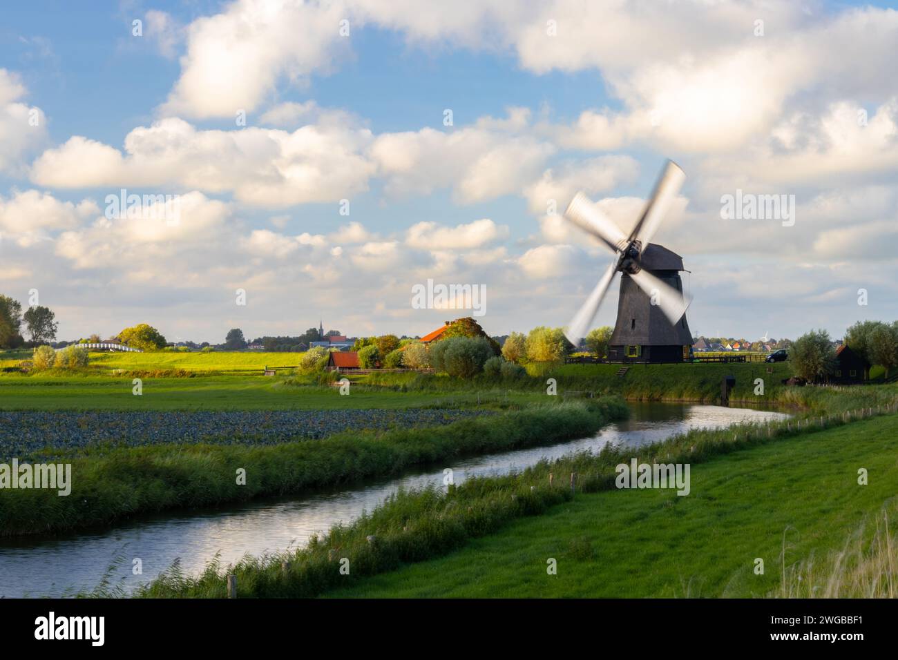 Windmill with rotating blades under a typical dutch summersky, partly ...