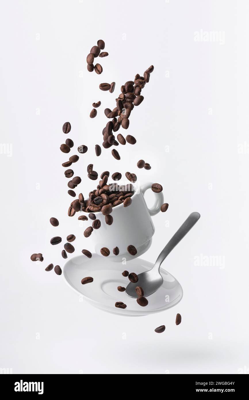 roasted coffee beans spilled from a floating cup and a teaspoon ...