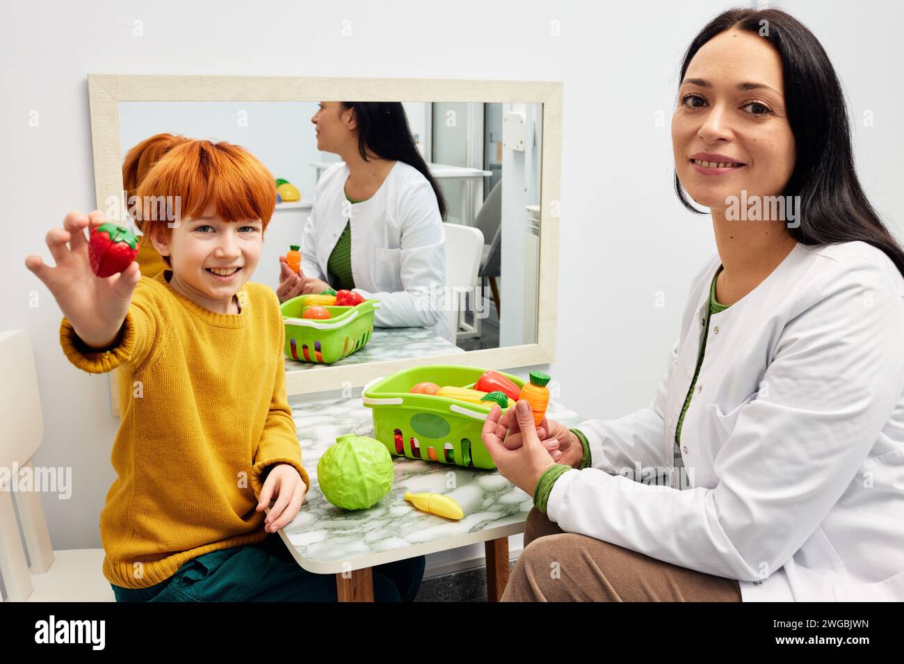 Cute boy and speech therapist using colorful plastic fruit and ...