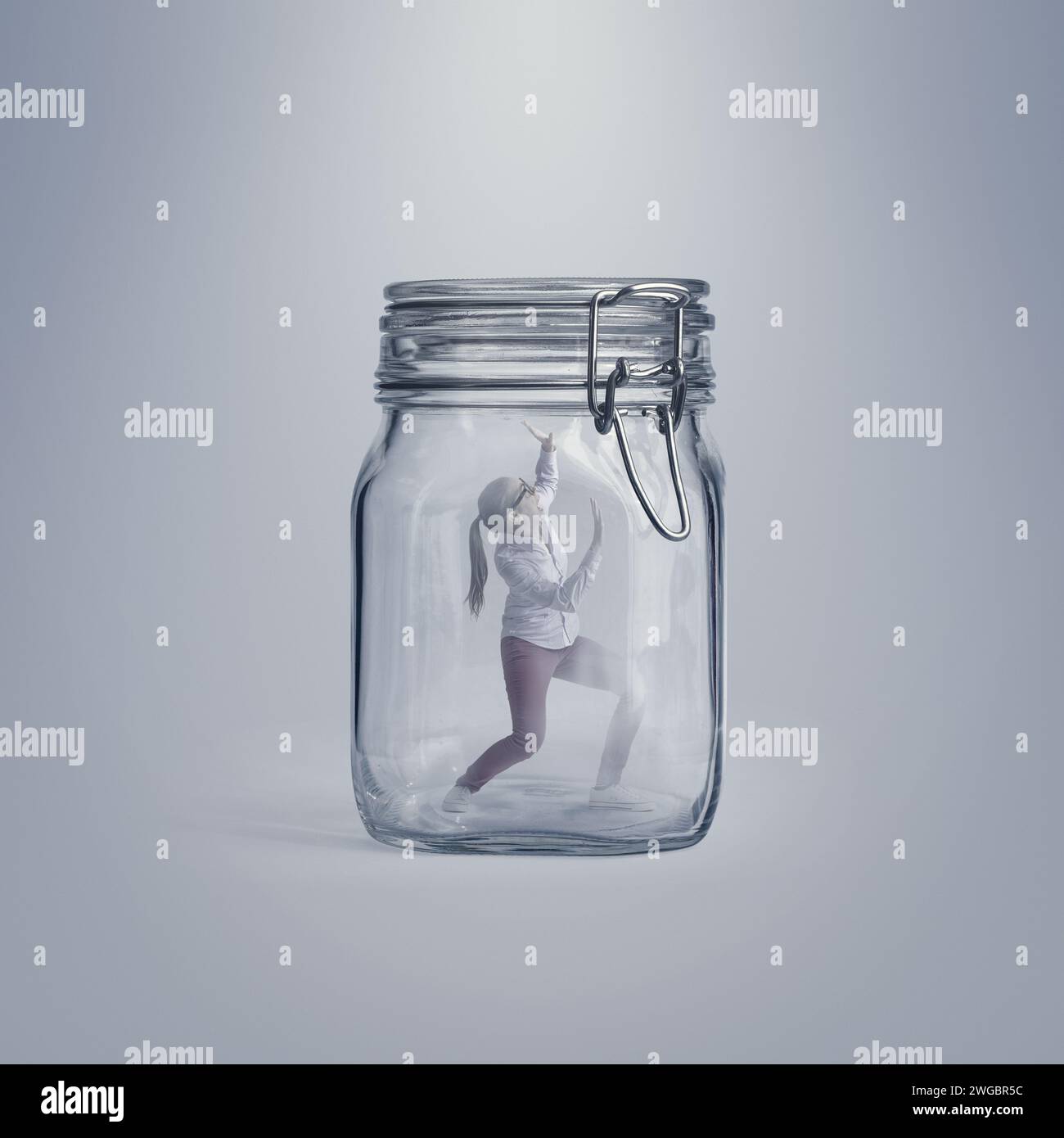 Scared young woman trapped in a huge glass jar, she is desperate and unable to escape Stock ...