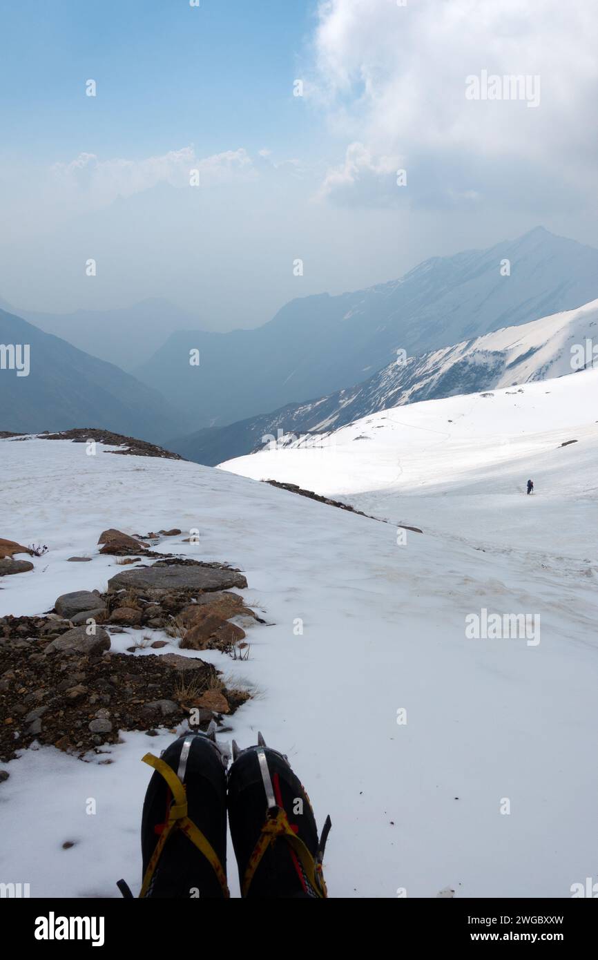 Woman wearing crampons sitting in mountain snow taking a break, Indian ...