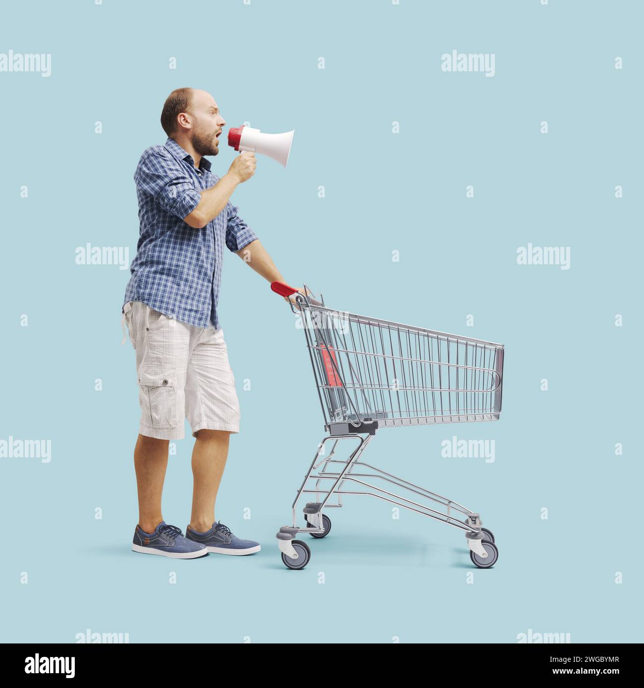 Loud man shouting into a megaphone and pushing an empty shopping cart ...