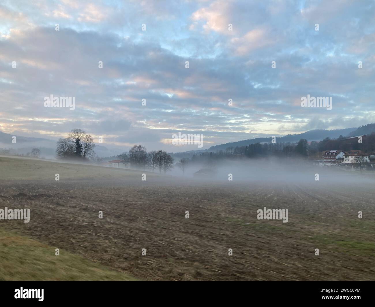 A sunset over a foggy field with houses and grass Stock Photo - Alamy