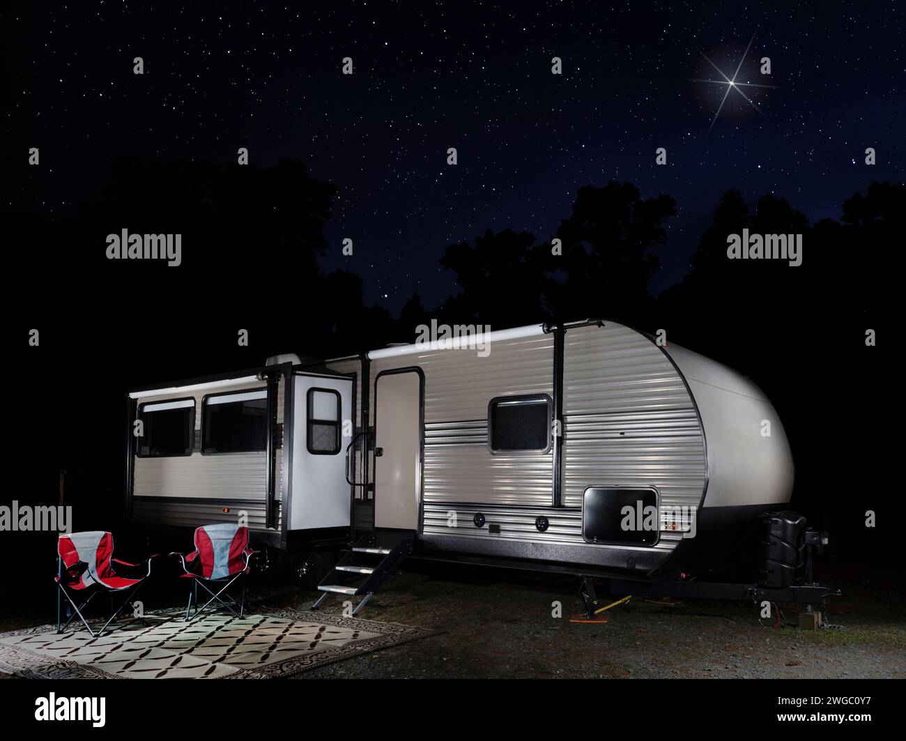 Camping trailer under a sky full of stars with one shining brightest ...
