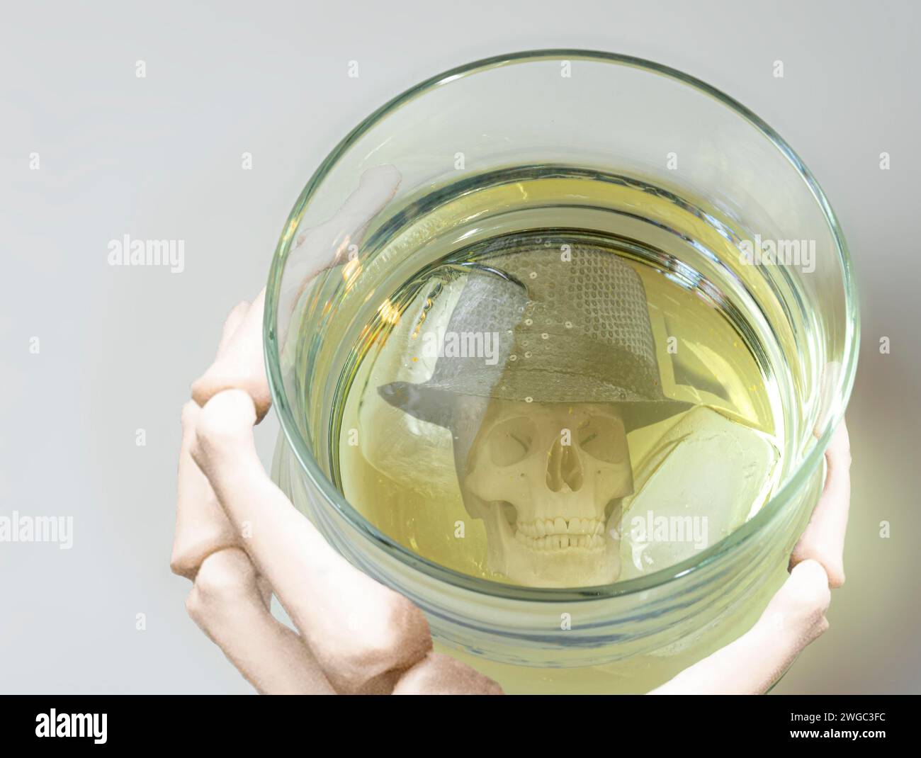 A skull tea bag draws in a glass with yellow liquid, held by a hand ...