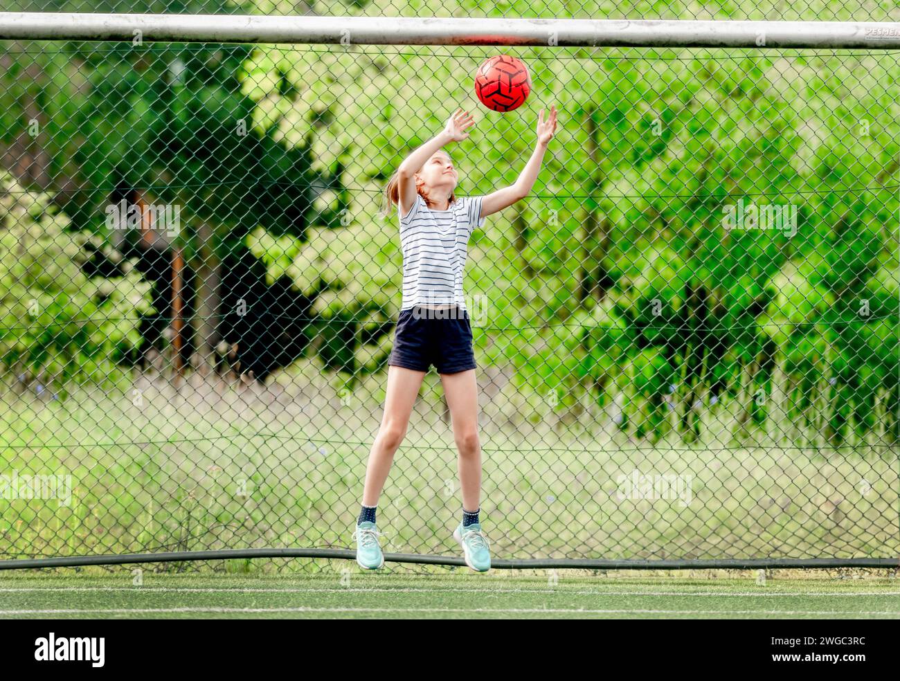 Pretty child girl catching football ball defending goal. Cute female ...
