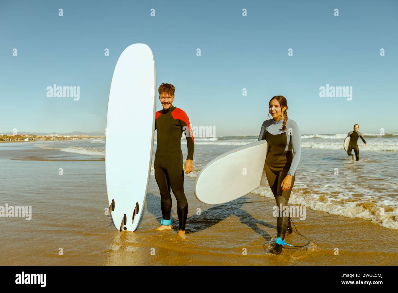 Group of surfers in wetsuit with his surfboards entering out of sea ...