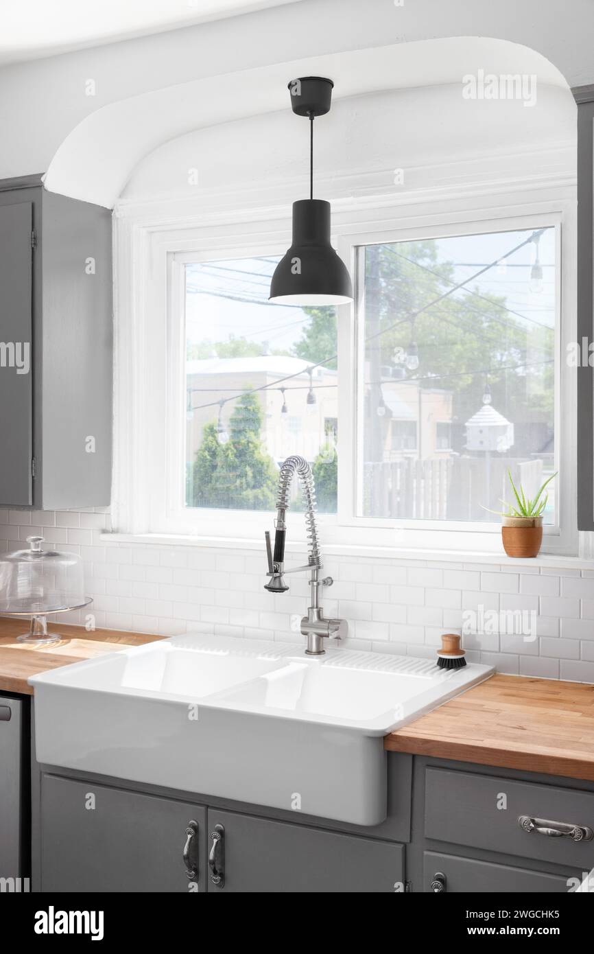 A kitchen sink detail with a butcher block wood countertop, white ...