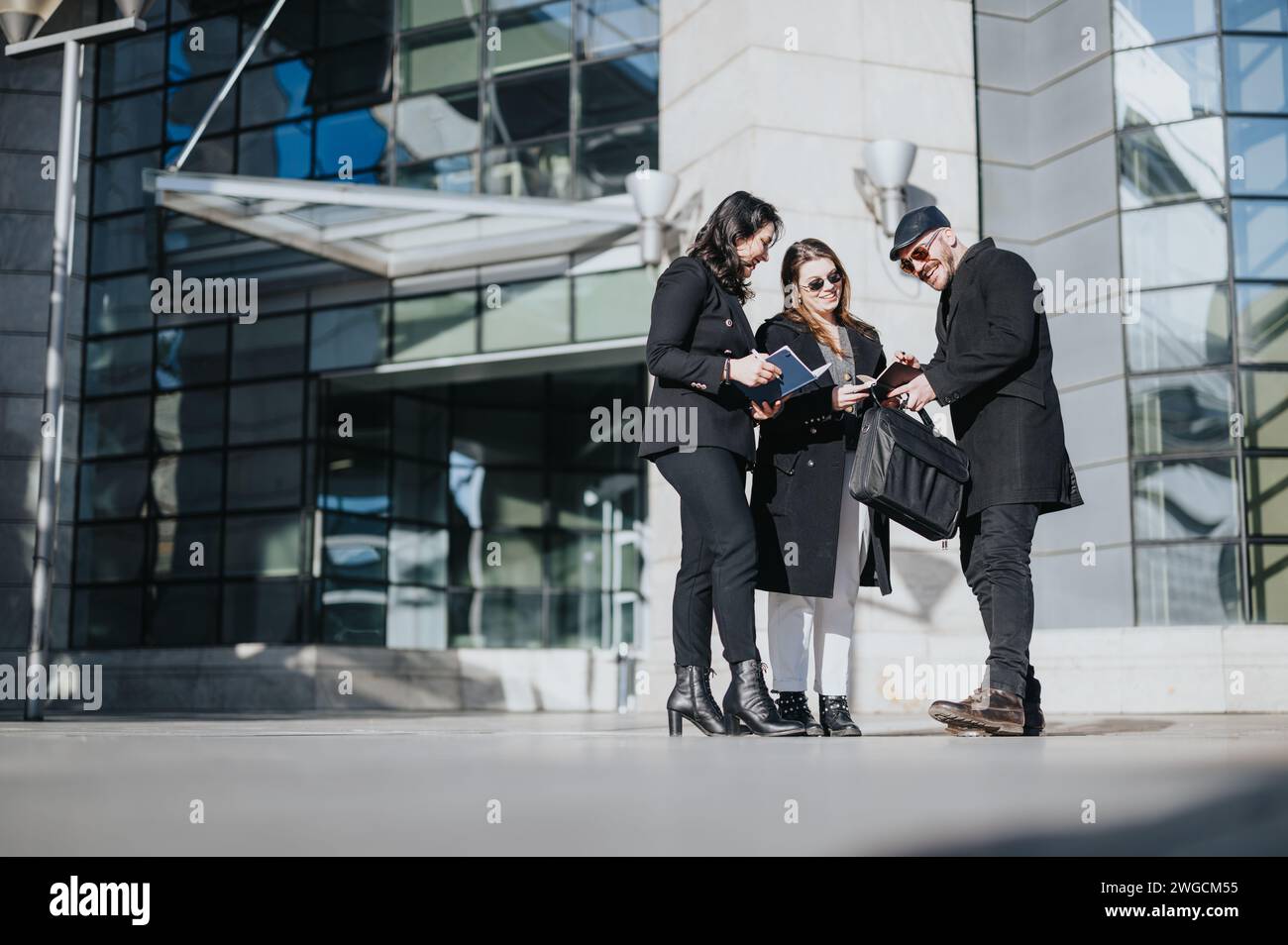 Three young people engaged in a serious business conversation outside a ...