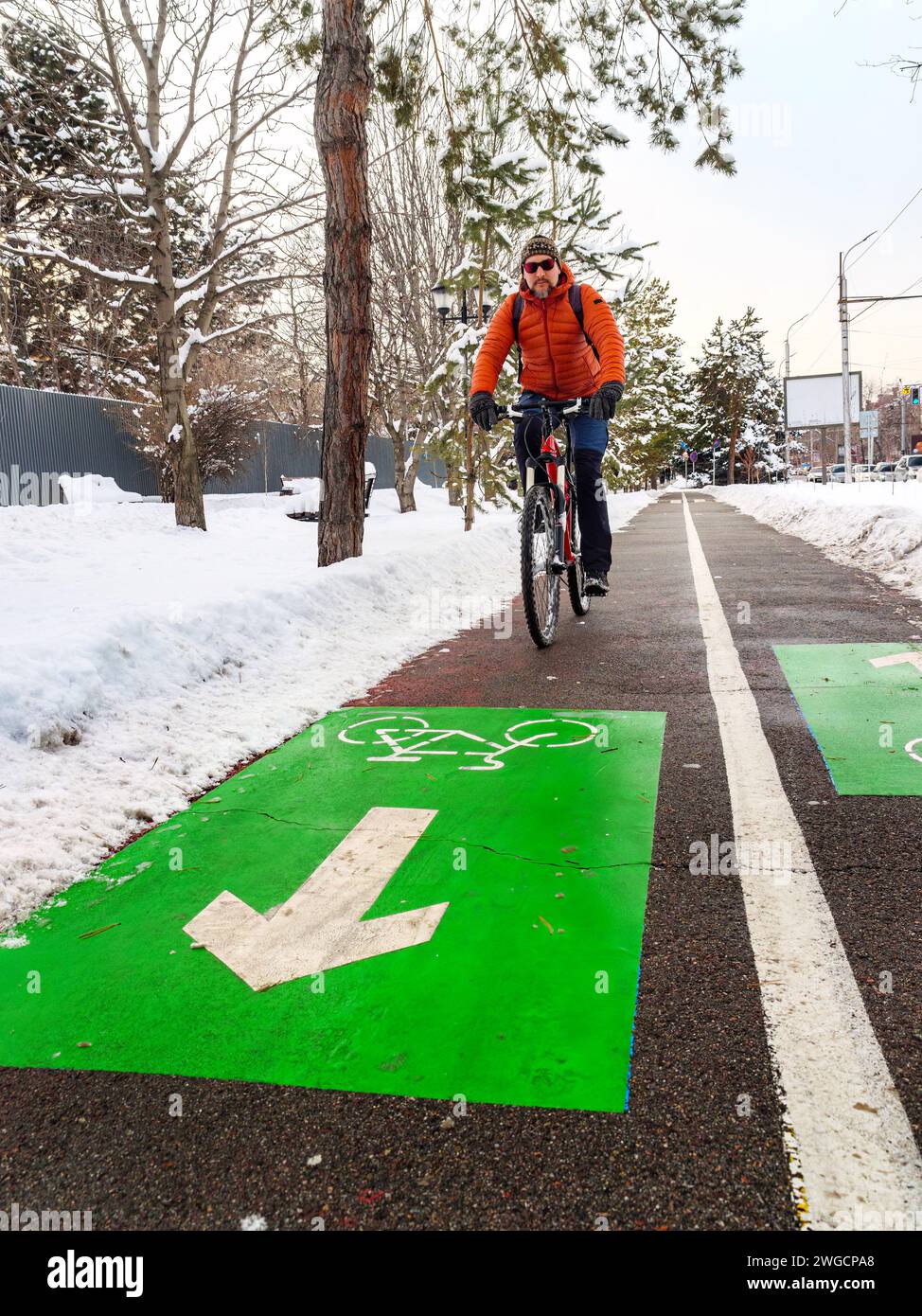 Vertical video footage of a guy in an orange jacket rides a bicycle ...
