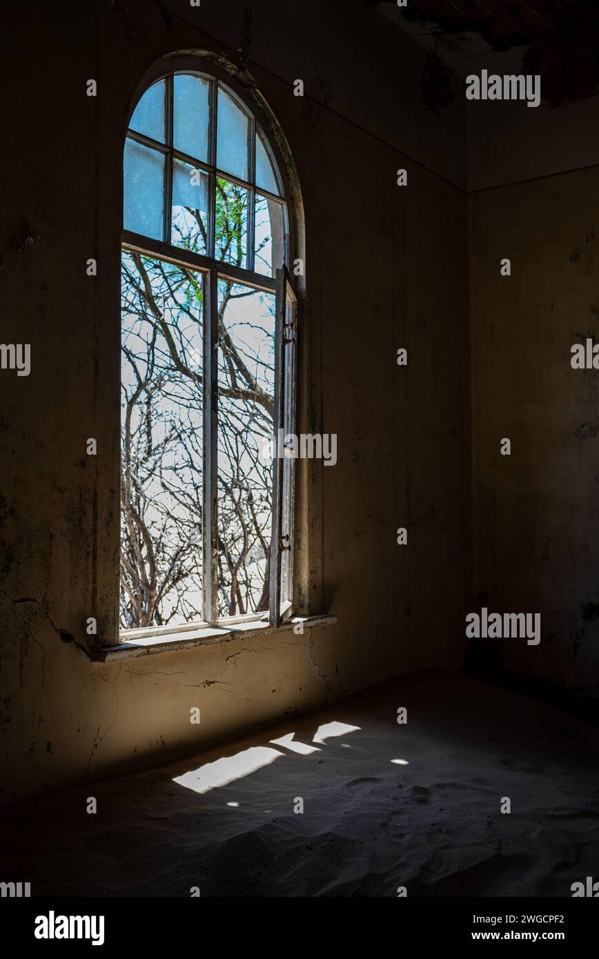 An abandoned interior space with an illuminated window in an old desert ...