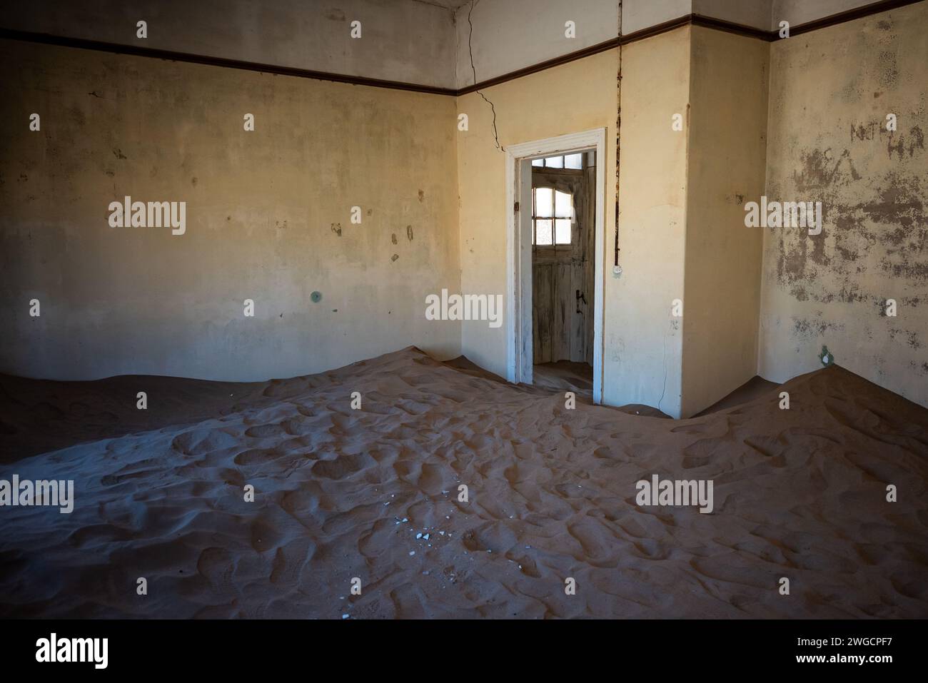 An abandoned room featuring a spacious sandy floor adjacent to an open ...