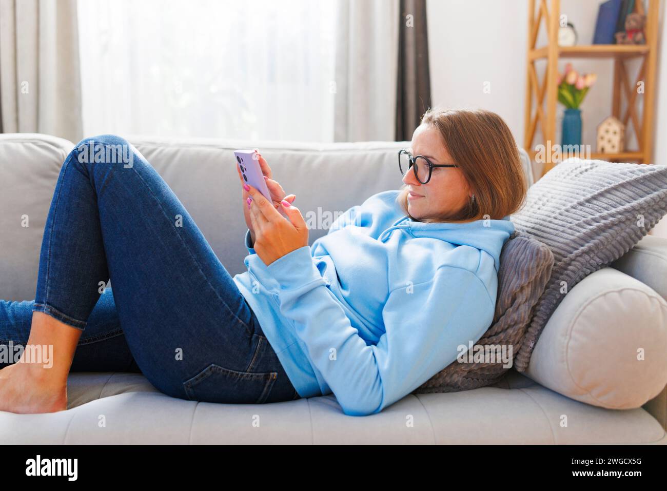 Using smartphone on couch woman hi-res stock photography and images - Alamy